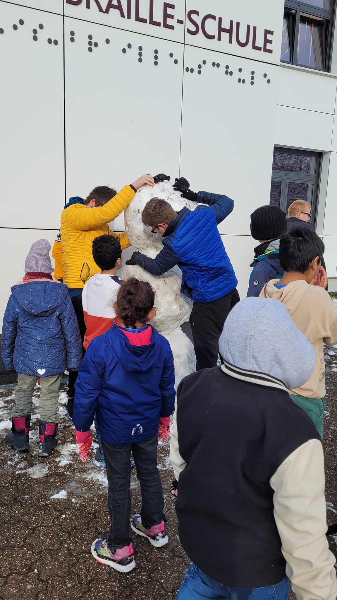 Schüler bauen gemeinsam einen Schneemann auf dem Schulhof | Louis ...